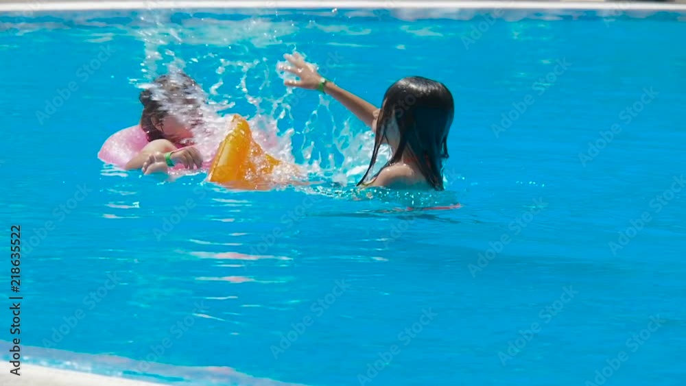 Children in the pool. Happy little girls are swimming in the pool ...