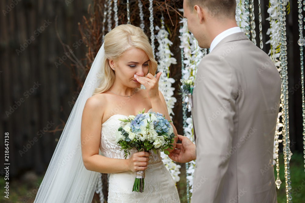 Wedding. Beautiful bride in dress with long veil crying during wedding ...