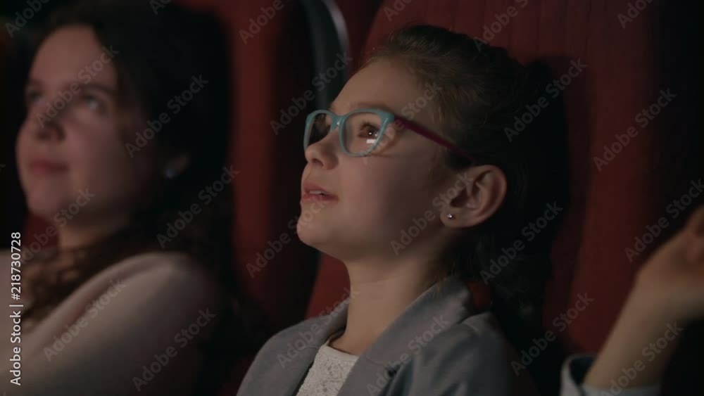 Beautiful girl in glasses watching cartoon film at movie theater. Girl ...