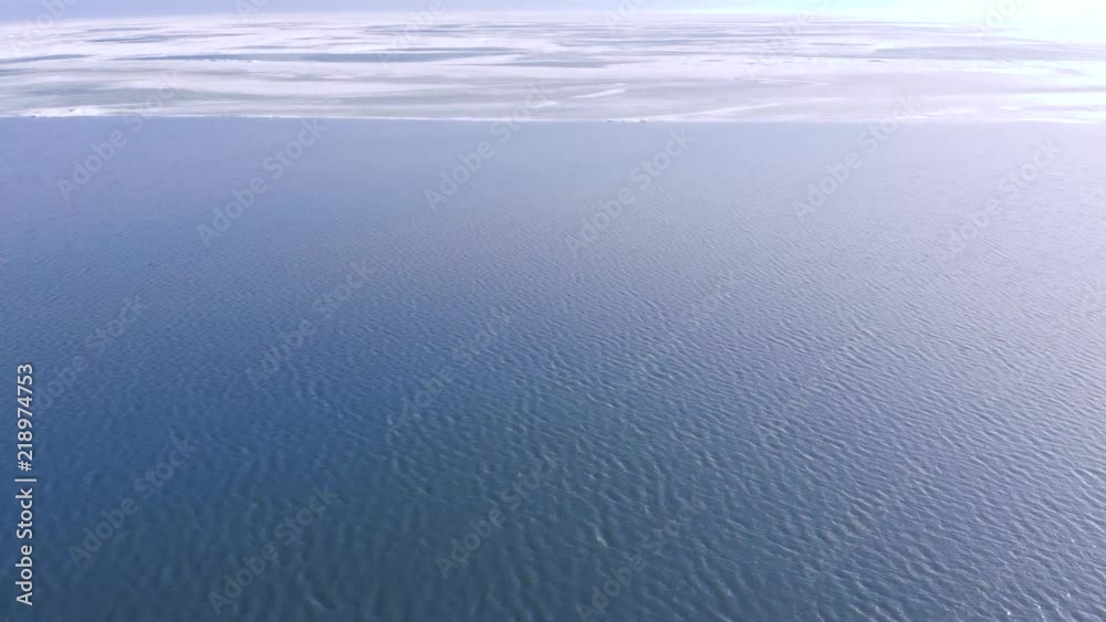 Melting frozen ice shelf on water.Drone shot flying over water to edge ...