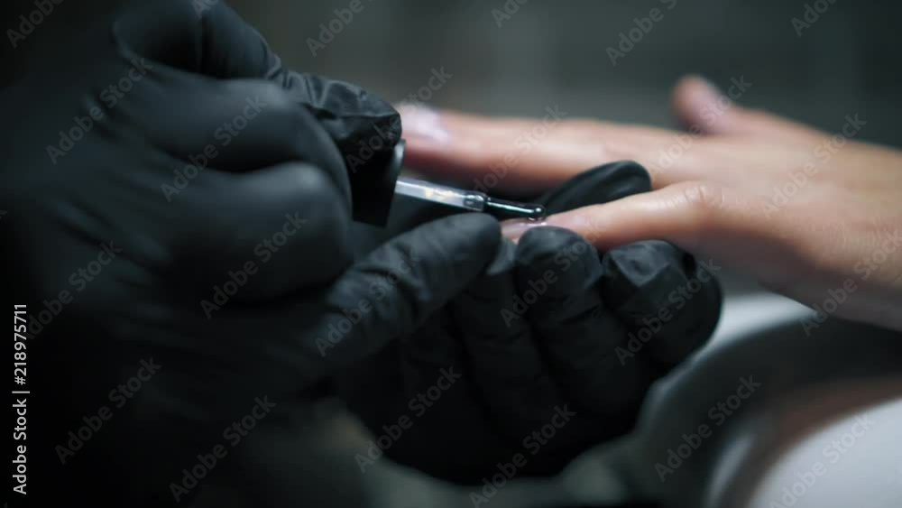 Manicure artist applying gel lacque on female nails in beauty salon ...