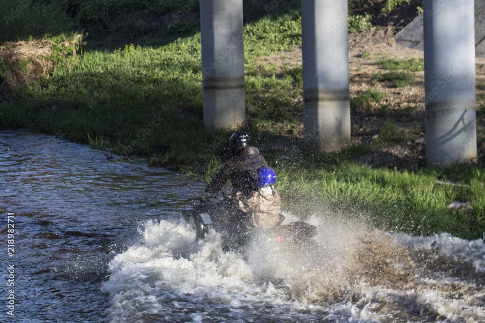 Motorcyclists on an ATV drove into the river. People wash an off-road ...