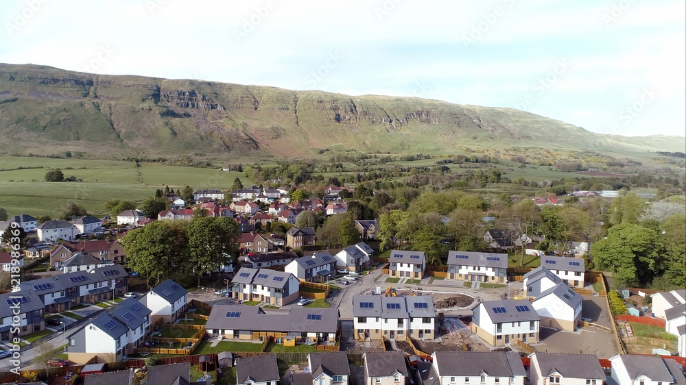 Low level aerial image over the rooftops of a rural housing estate with ...