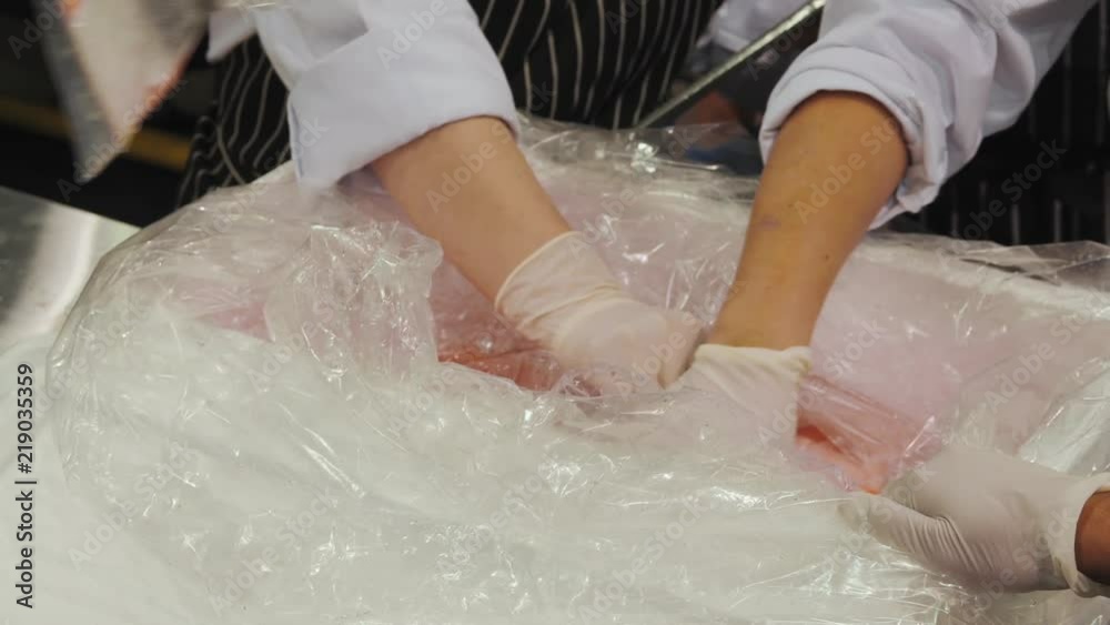 Chefs reaching into chiller box pulling out large raw fresh salmon ...