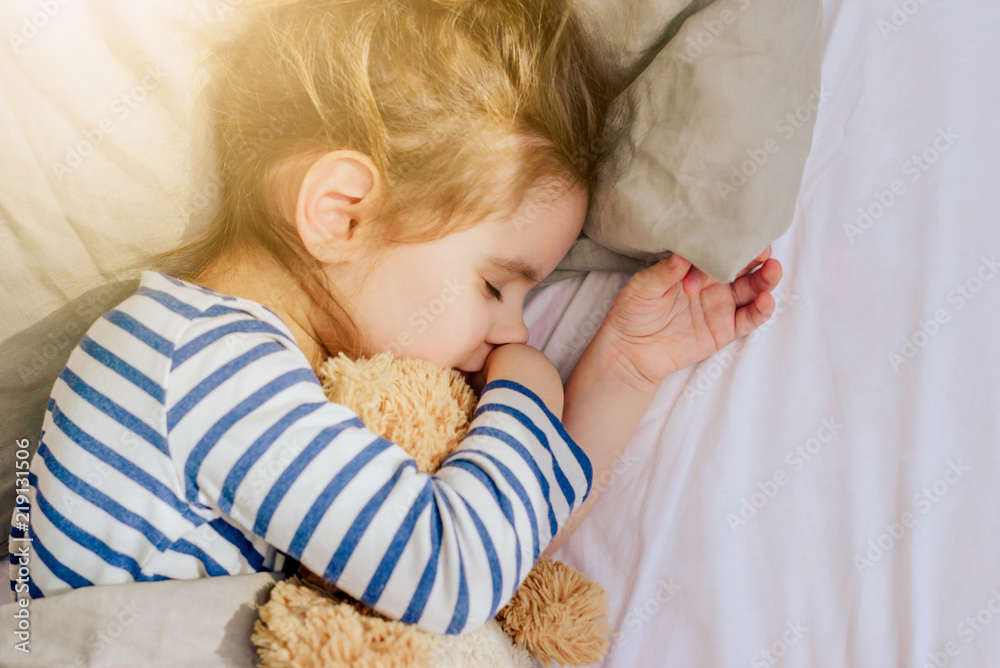 Beautiful baby girl sleeping in my own bed at home with a favorite toy ...
