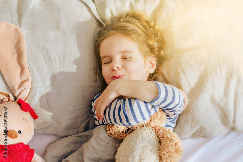 Beautiful baby girl sleeping in my own bed at home with a favorite toy ...