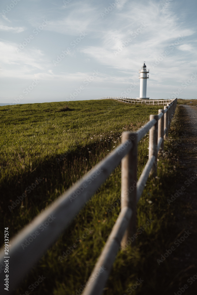 Fence and field with lighthouse on background Stock Photo | Adobe Stock
