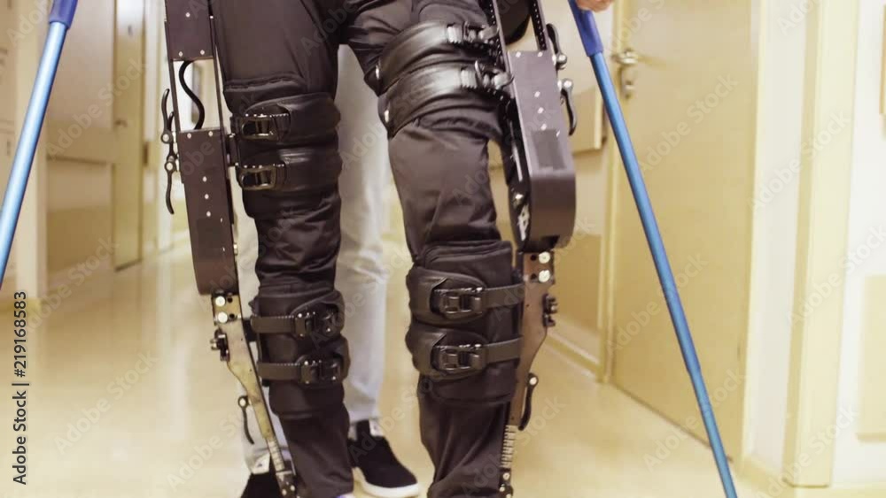 Legs of disable man in in the robotic exoskeleton walking through the ...