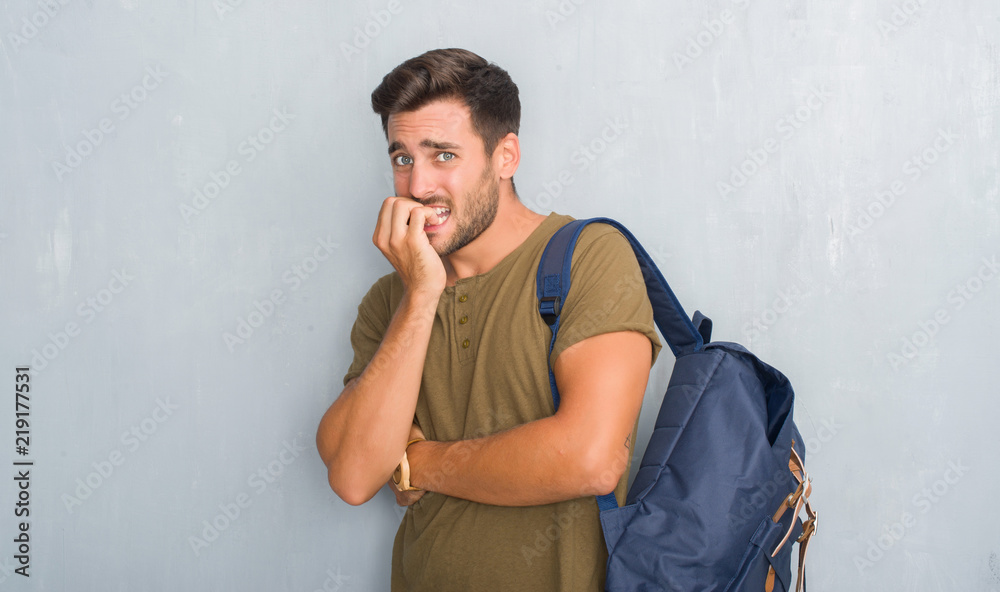 Handsome tourist young man over grey grunge wall wearing backpack ...