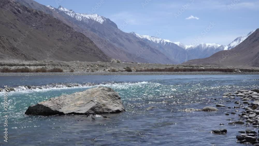 A river flows over rocks in this beautiful scene in the himalaya ...