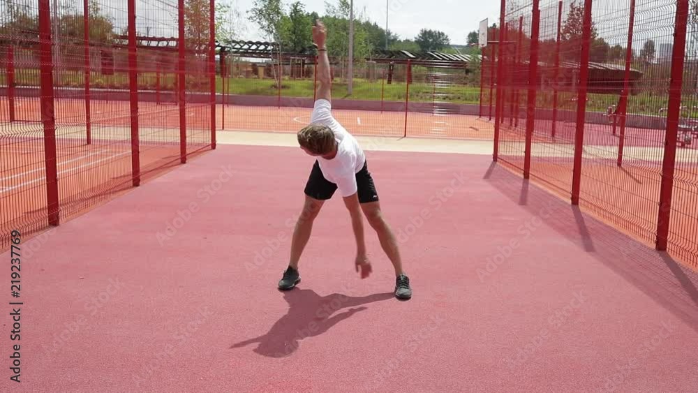 Fitness athlete doing running warm up in summer urban park. Windmill ...