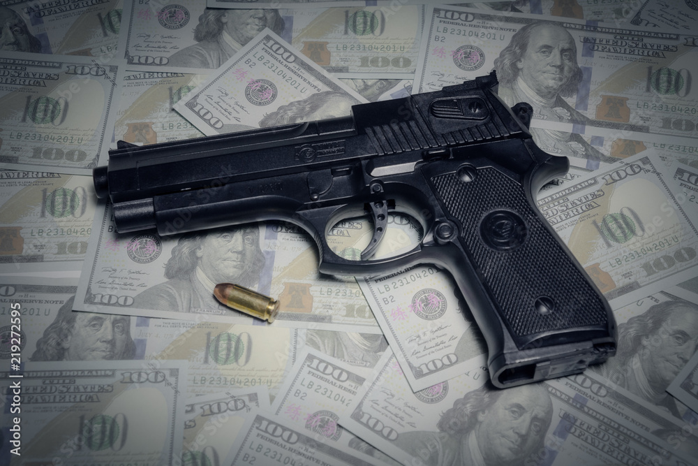 A gun and a bullet over a floor of US Dollar banknotes. Stock Photo ...