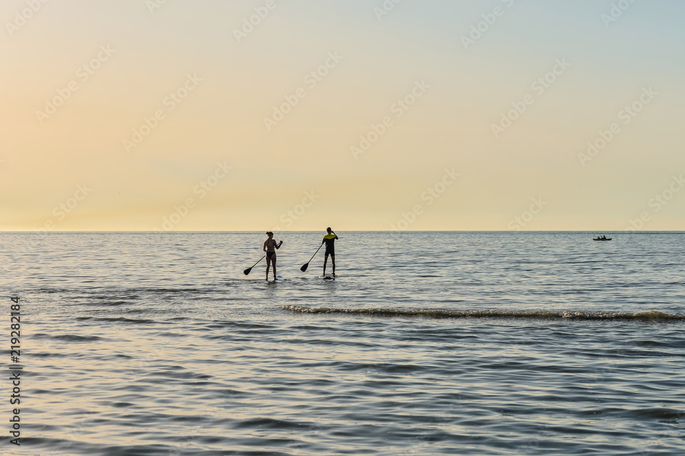 jeune couple en stand up face au soleil couchant Stock Photo | Adobe Stock