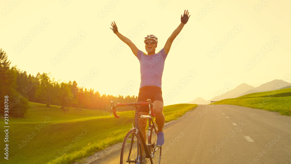 LENS FLARE: Professional biker raising his arms victoriously after ...
