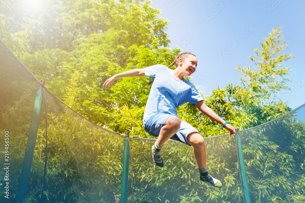 Excited girl jumping on the trampoline outdoors Stock Photo | Adobe Stock