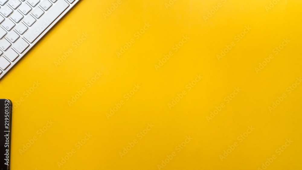 Keyboard with smartphone yellow background business concept desk table ...