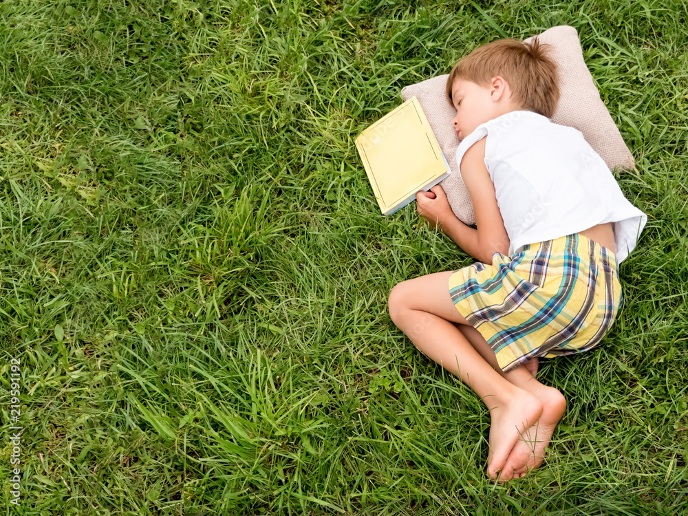 Boy with book on the grass in the park. Reading concept background ...
