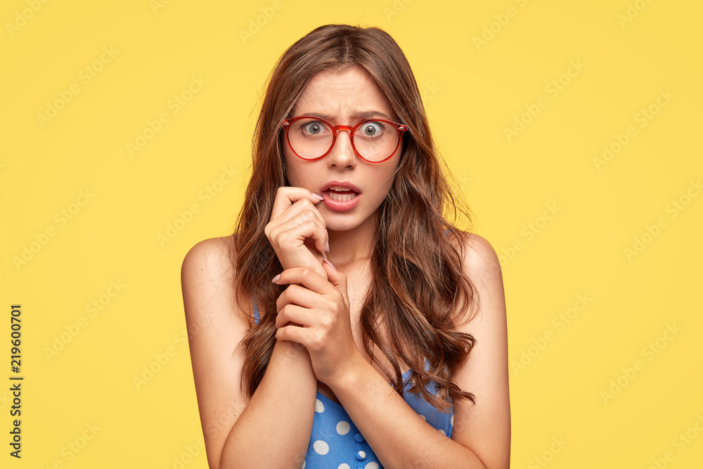 Displeased surprised female model has wavy dark hair, looks with ...