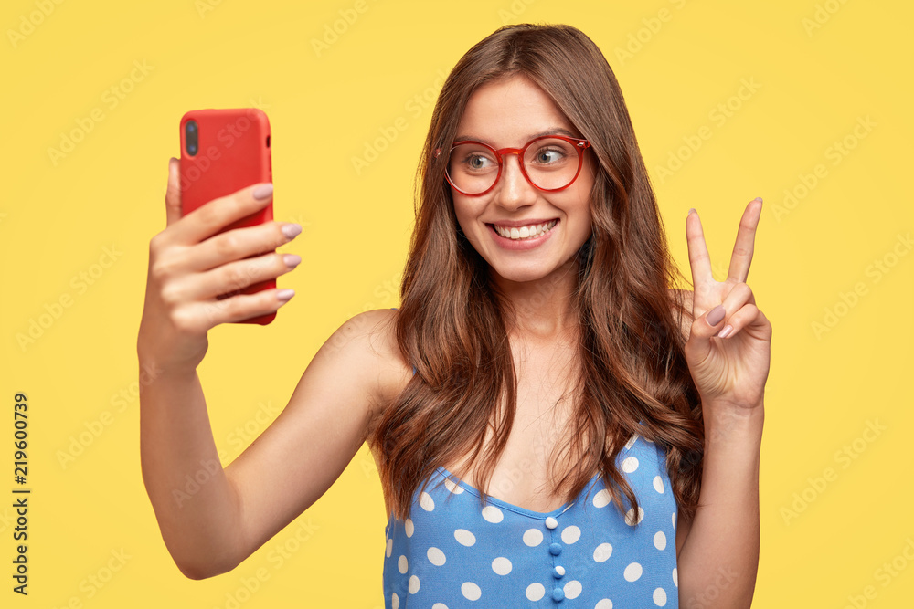 Beautiful female youngster makes peace gesture while poses for making ...