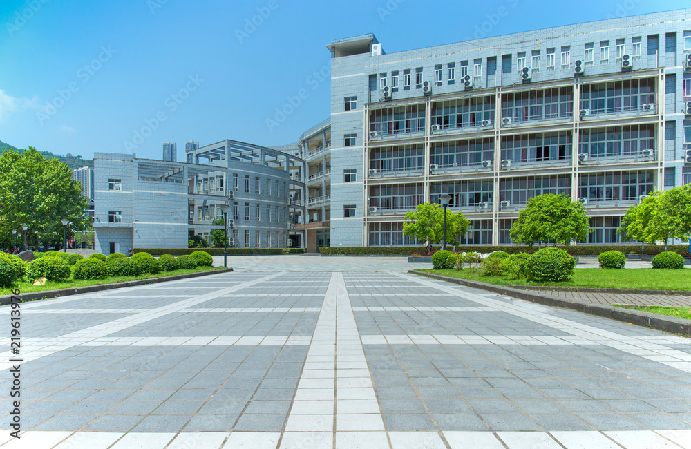 University school building and grass park outside the gate in sunny ...