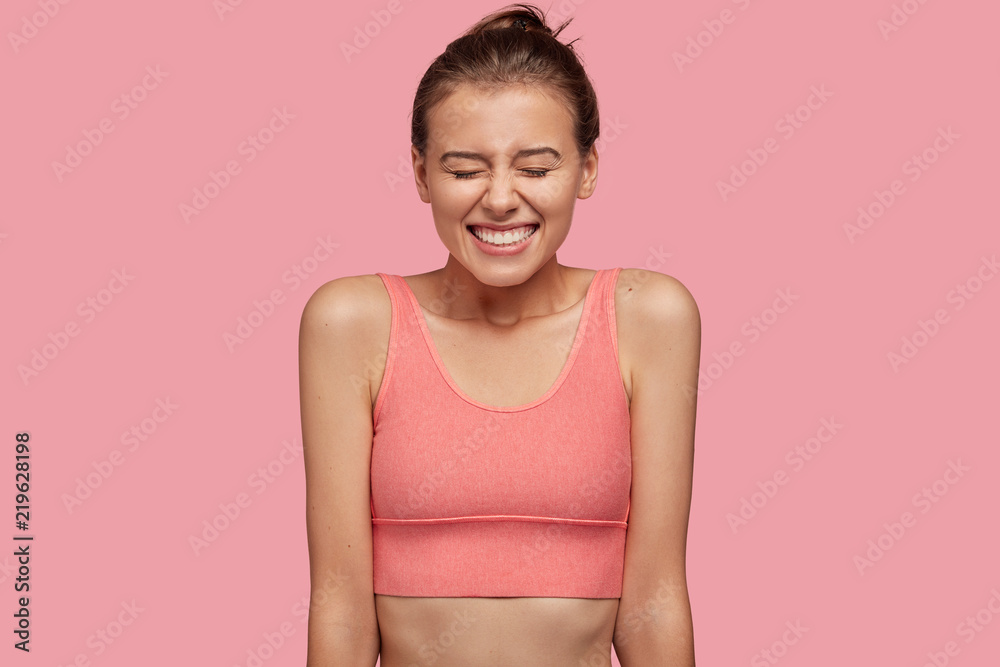 Positive female in sports top, giggles happily, likes gymnastics ...