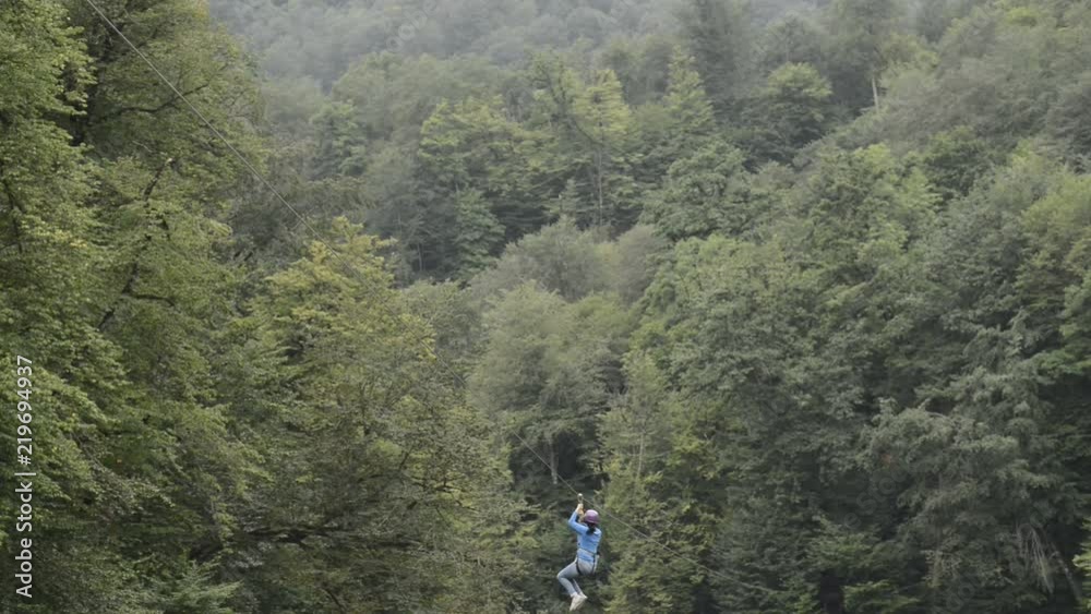 Exciting adventure activity in mountains. woman hanging on a rope-way ...