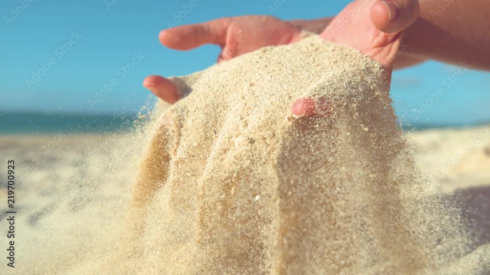 SLOW MOTION, CLOSE UP: Young woman scatters white sand with her gentle ...