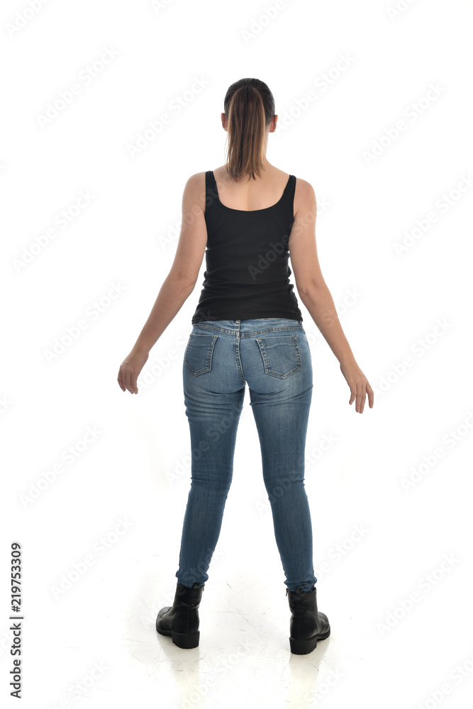 full length portrait of brunette girl wearing black single and jeans ...