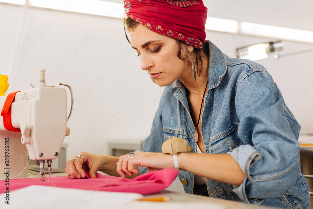 Serious process. Professional experienced dressmaker sitting at the ...