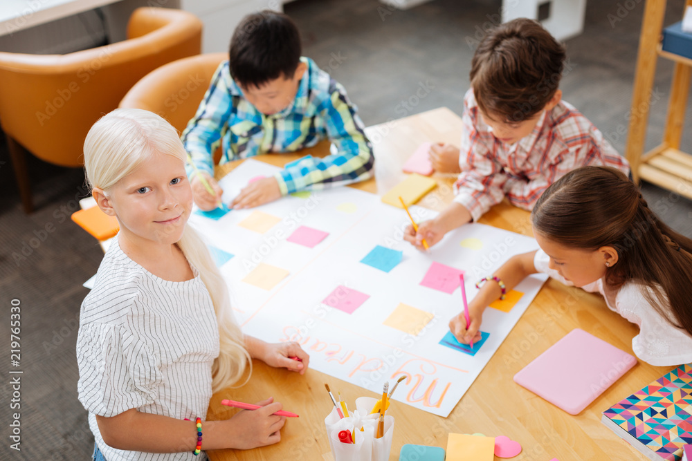 Nice girl. Pretty girl spending time with classmates while drawing a ...