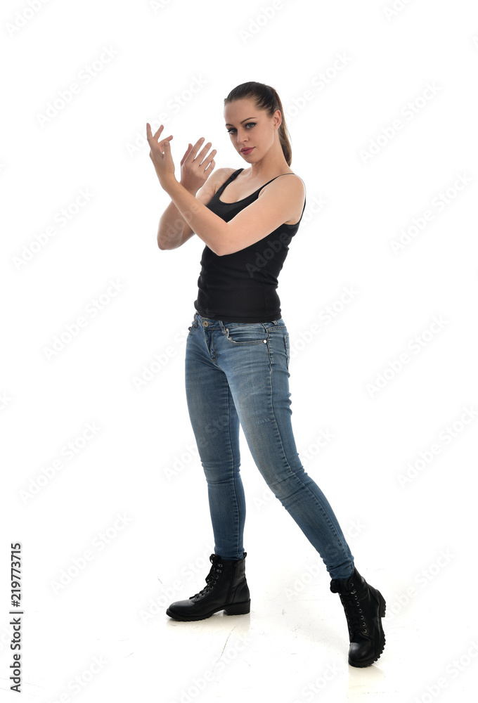 full length portrait of brunette girl wearing black single and jeans ...