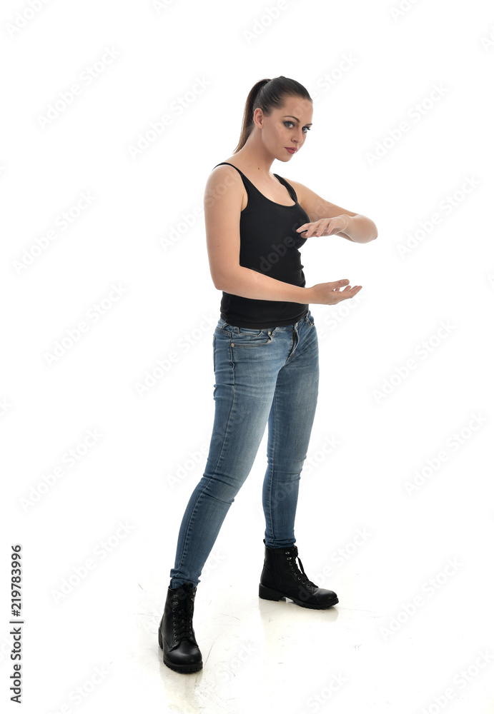 full length portrait of brunette girl wearing black single and jeans ...