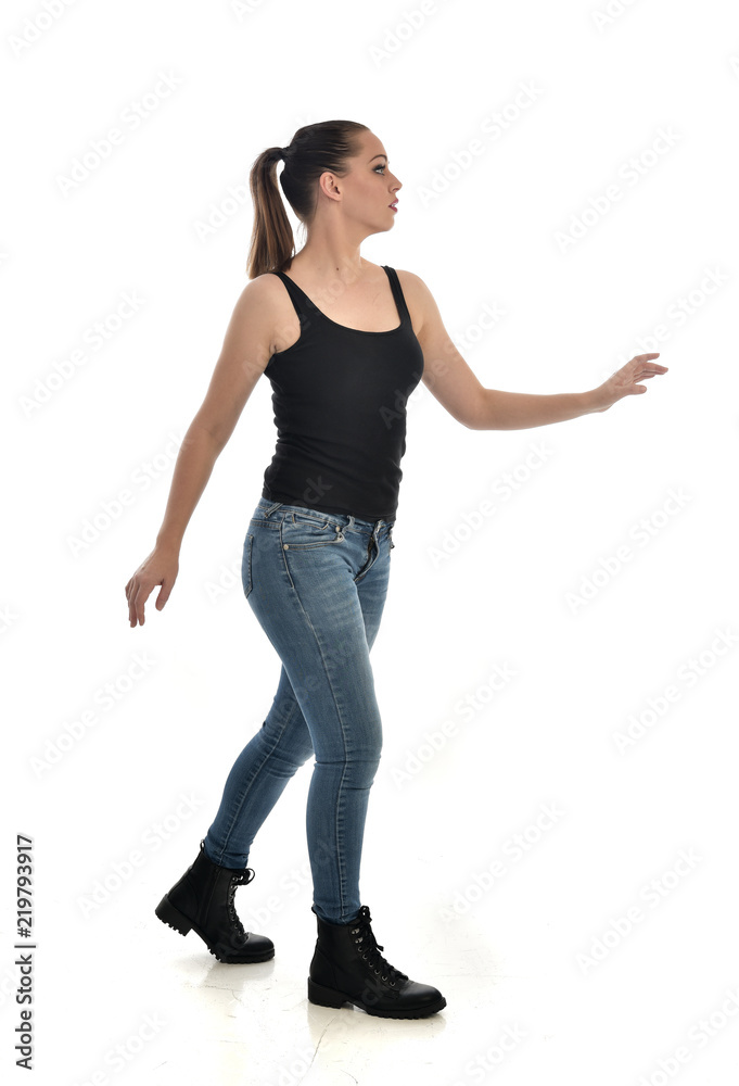 full length portrait of brunette girl wearing black single and jeans ...