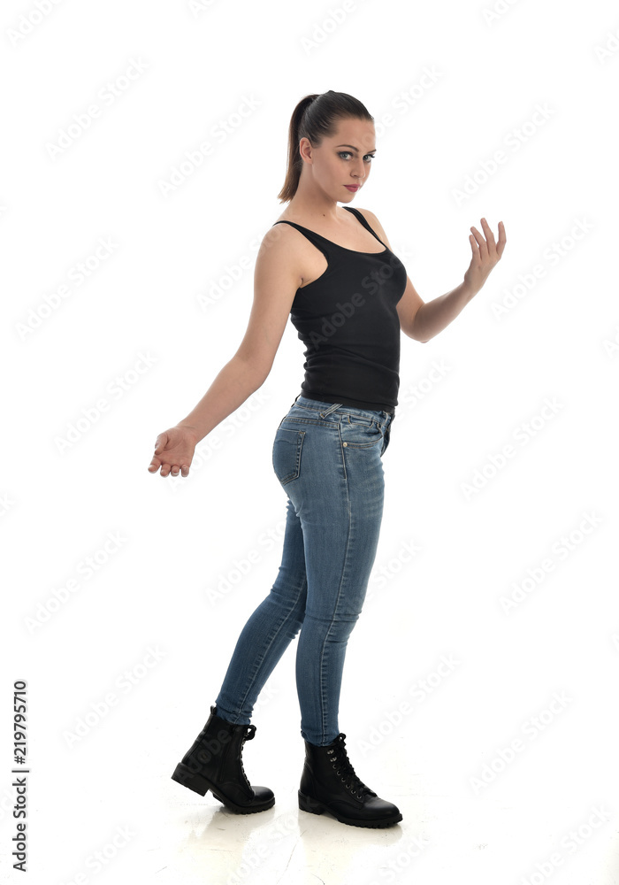 full length portrait of brunette girl wearing black single and jeans ...