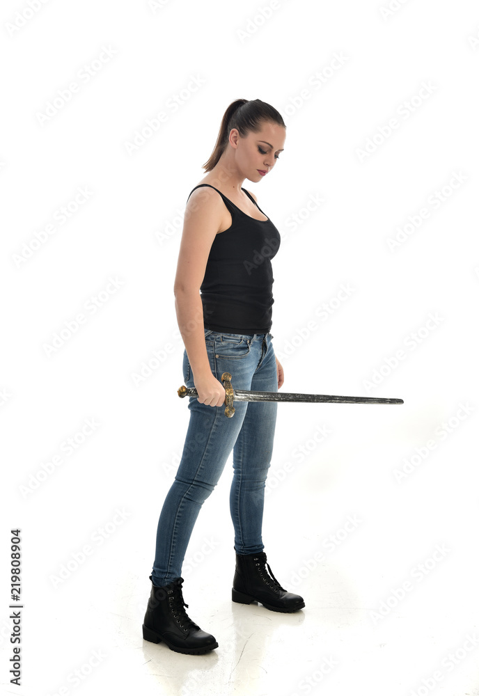 full length portrait of brunette girl wearing black single and jeans ...