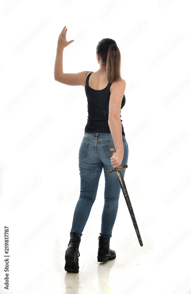full length portrait of brunette girl wearing black single and jeans ...