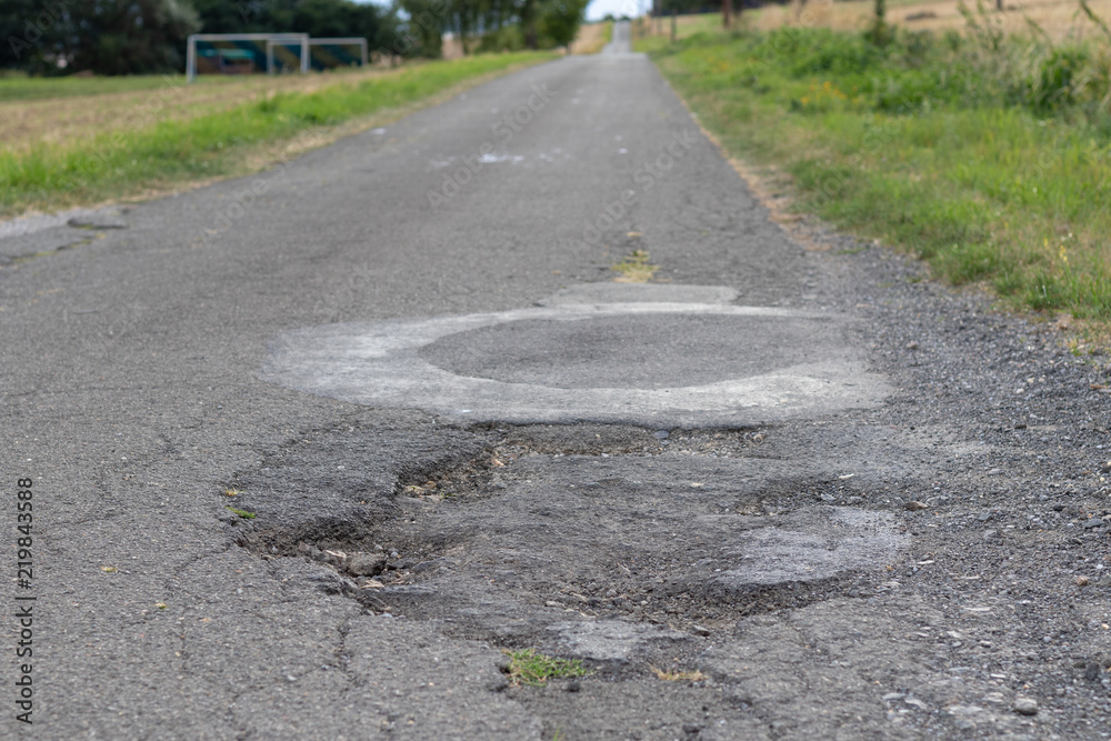 Pothole on a concrete way in a rural landscape Stock Photo | Adobe Stock