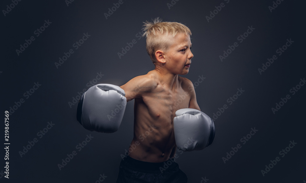Shirtless young boxer with blonde hair wearing boxing gloves shows a ...