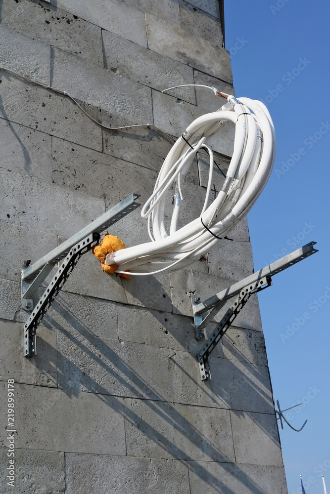 Flexible pipes with thermal insulation hang on the wall of a modern ...