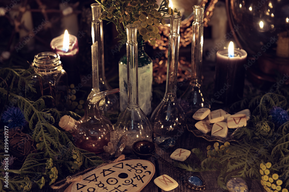 Still life with alchemy ritual objects, old bottles, herbs and black ...