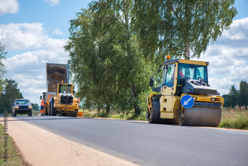 Road construction workers repairing highway road on sunny summer day ...