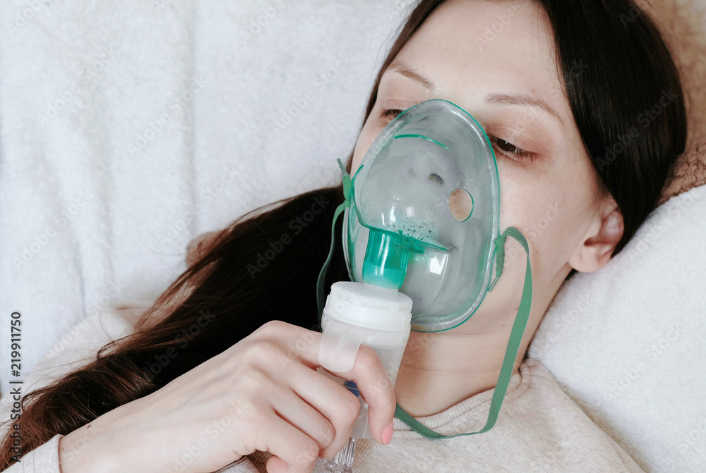 Use nebulizer and inhaler for the treatment. Young woman's face ...