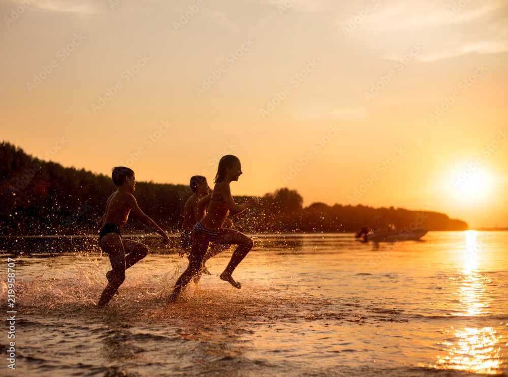 Happy children playing on the beach at the sunset time Stock Photo ...