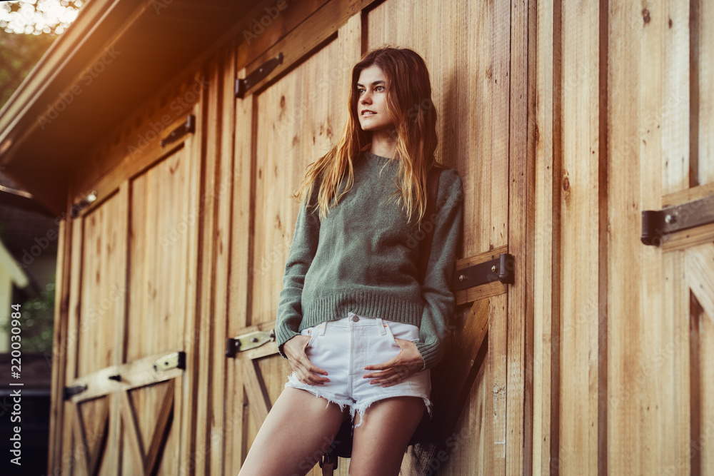 Beautiful young adult country woman posing near barn farm wooden doors ...