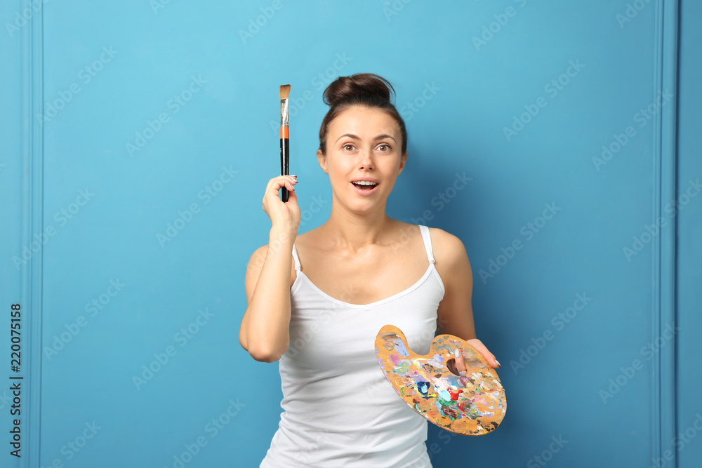 Emotional female artist with brush and paint palette on color ...