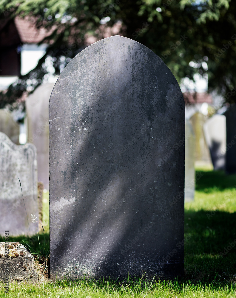 White marble gravestone (blank) in the shape of a cross. Trees and ...