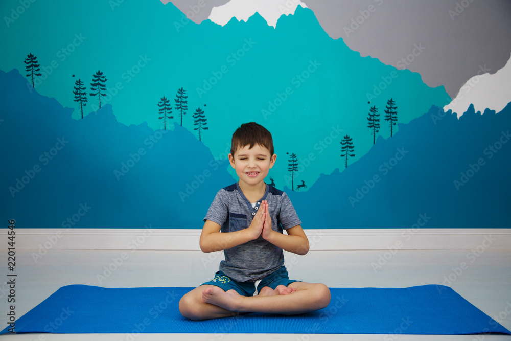 Cute caucasian boy does yoga in his room with a beautiful mountain ...