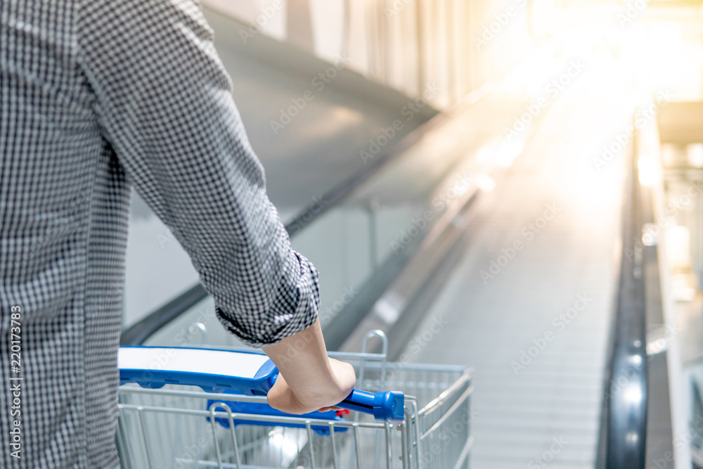 Male hand shopper pushing shopping cart (trolley) on travelator ...
