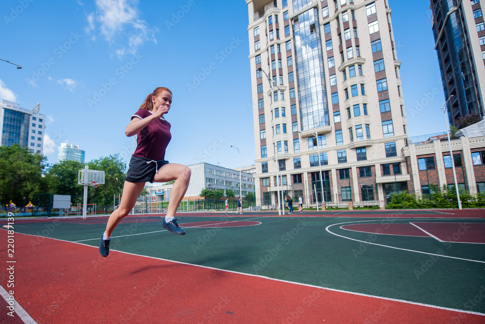 Red-haired young girl runs in the stadium. Student delivers standards ...
