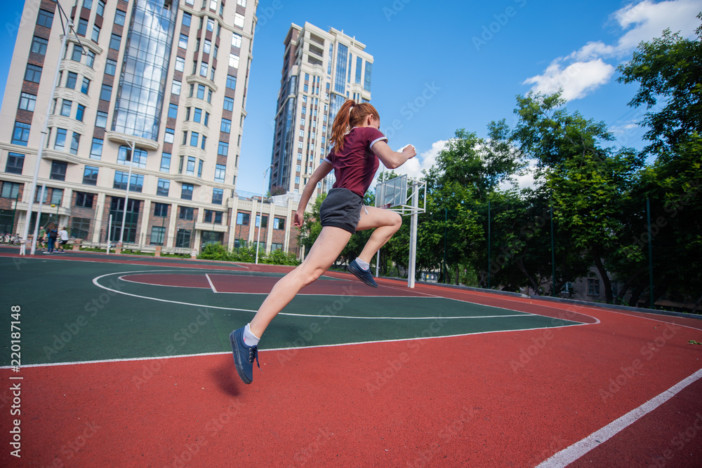 Red-haired young girl runs in the stadium. Student delivers standards ...